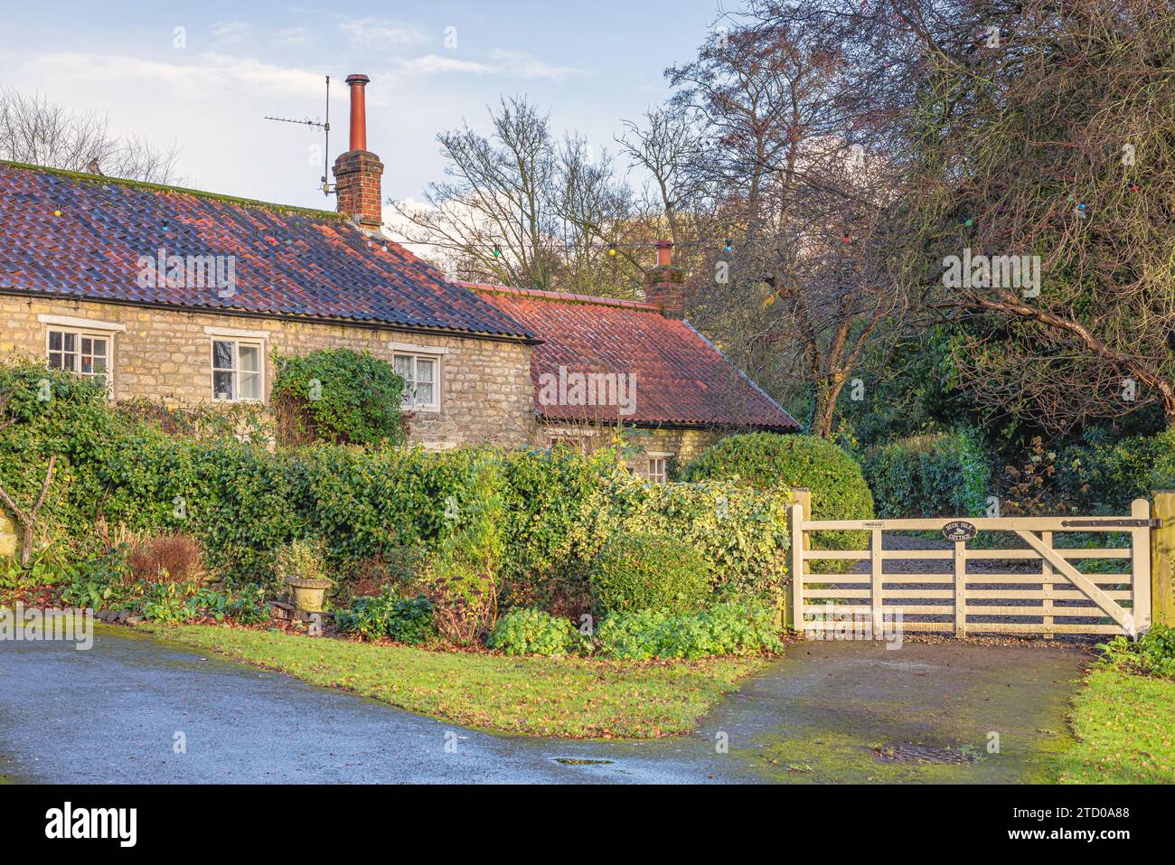 Stone-built country cottage with red-tiled roof and chimneys. A wooden ...