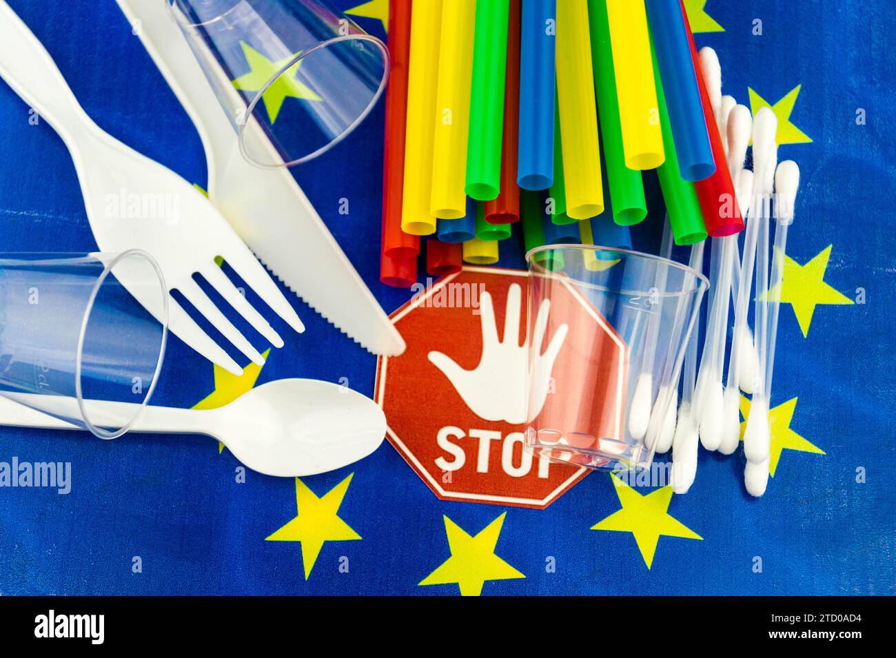 Plastic straws, cups, cutlery and cotton buds on European flag with ...