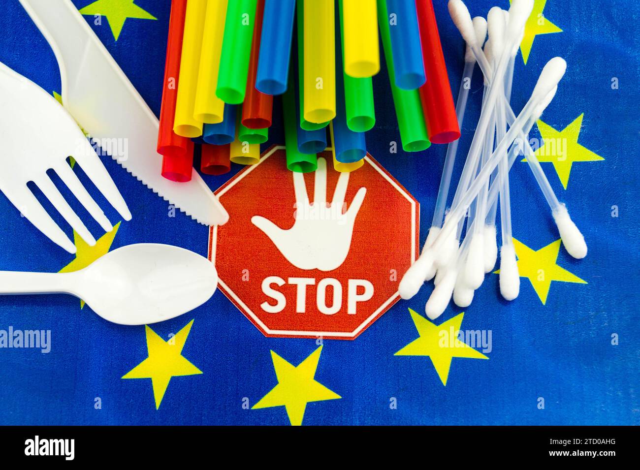 Plastic straws, cutlery and cotton buds on European flag with stop sign ...