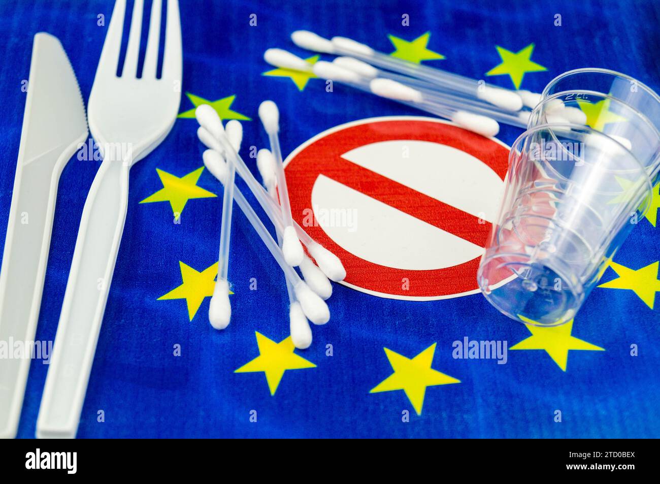 Plastic objects, cutlery, cups and cotton buds on European flag with ...