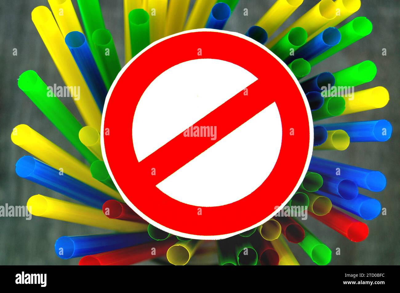Colorful plastic straws in a cup in supervision, with prohibition sign ...