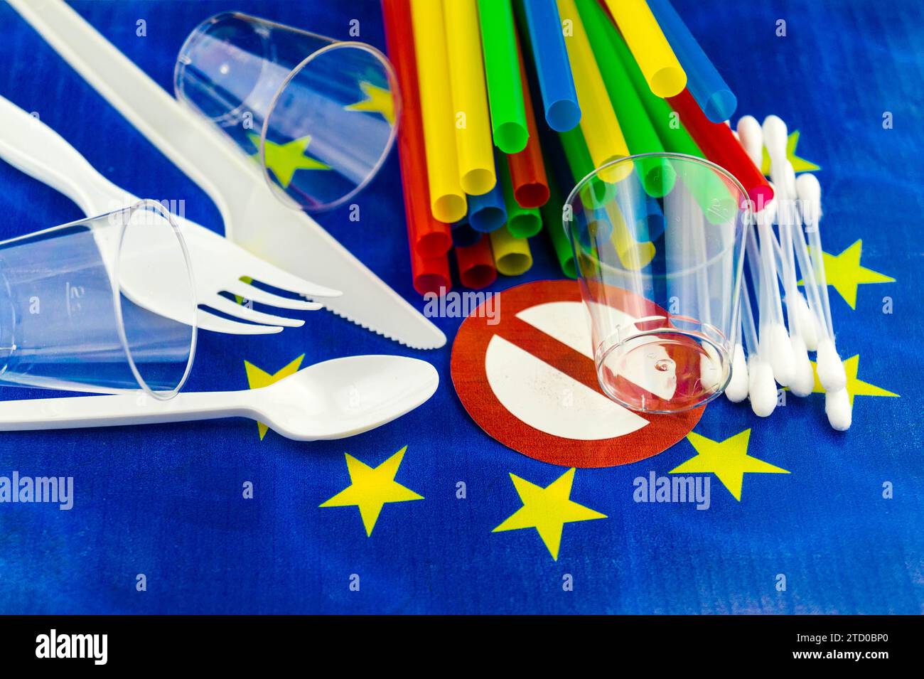 Plastic straws, cups, cutlery and cotton buds on European flag with ...