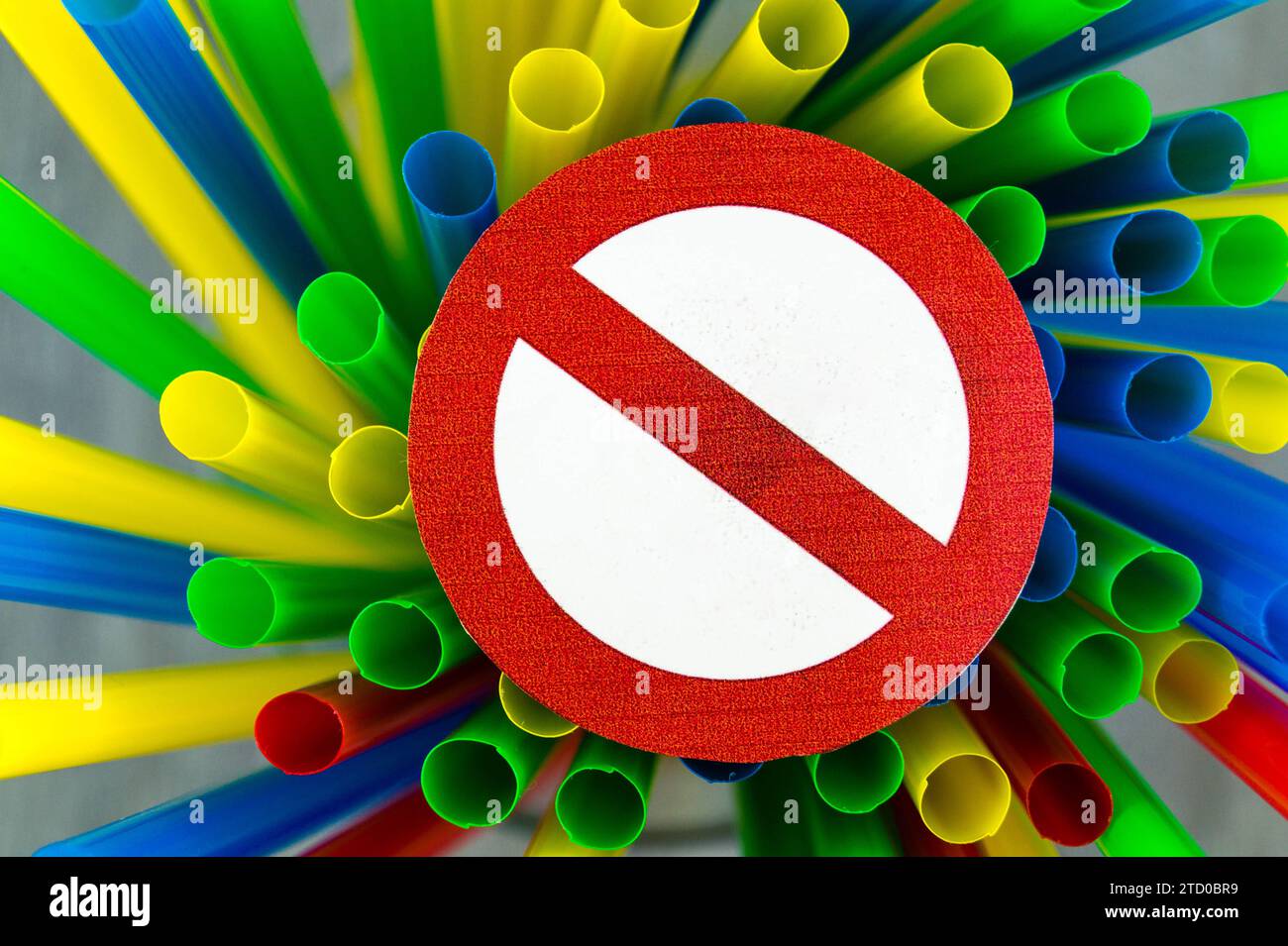 Colorful plastic straws in a cup in supervision, with prohibition sign ...