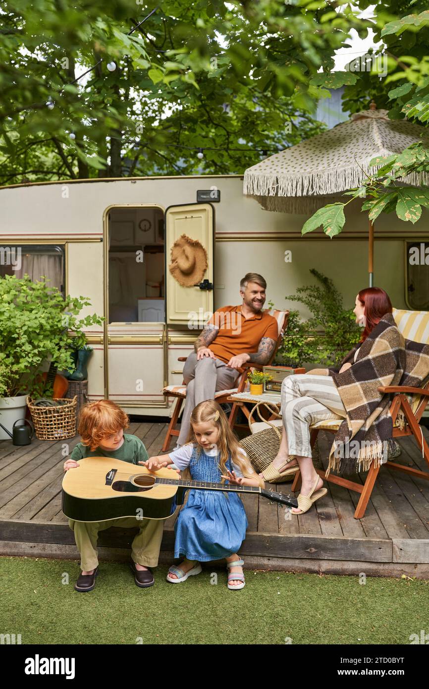 children learning to play acoustic guitar while parents sitting in deck ...