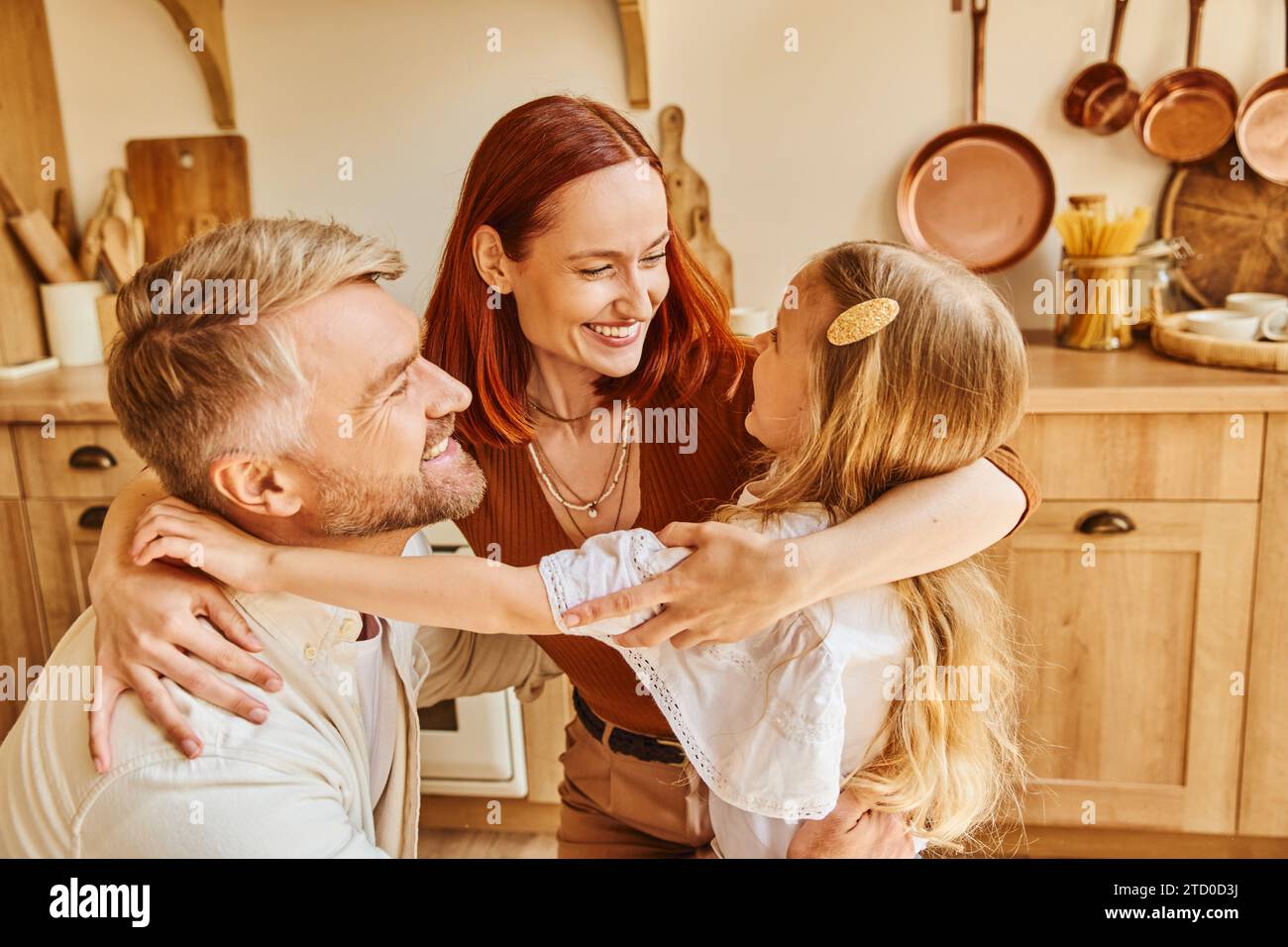 loving parents with adorable daughter embracing in cozy kitchen at home ...