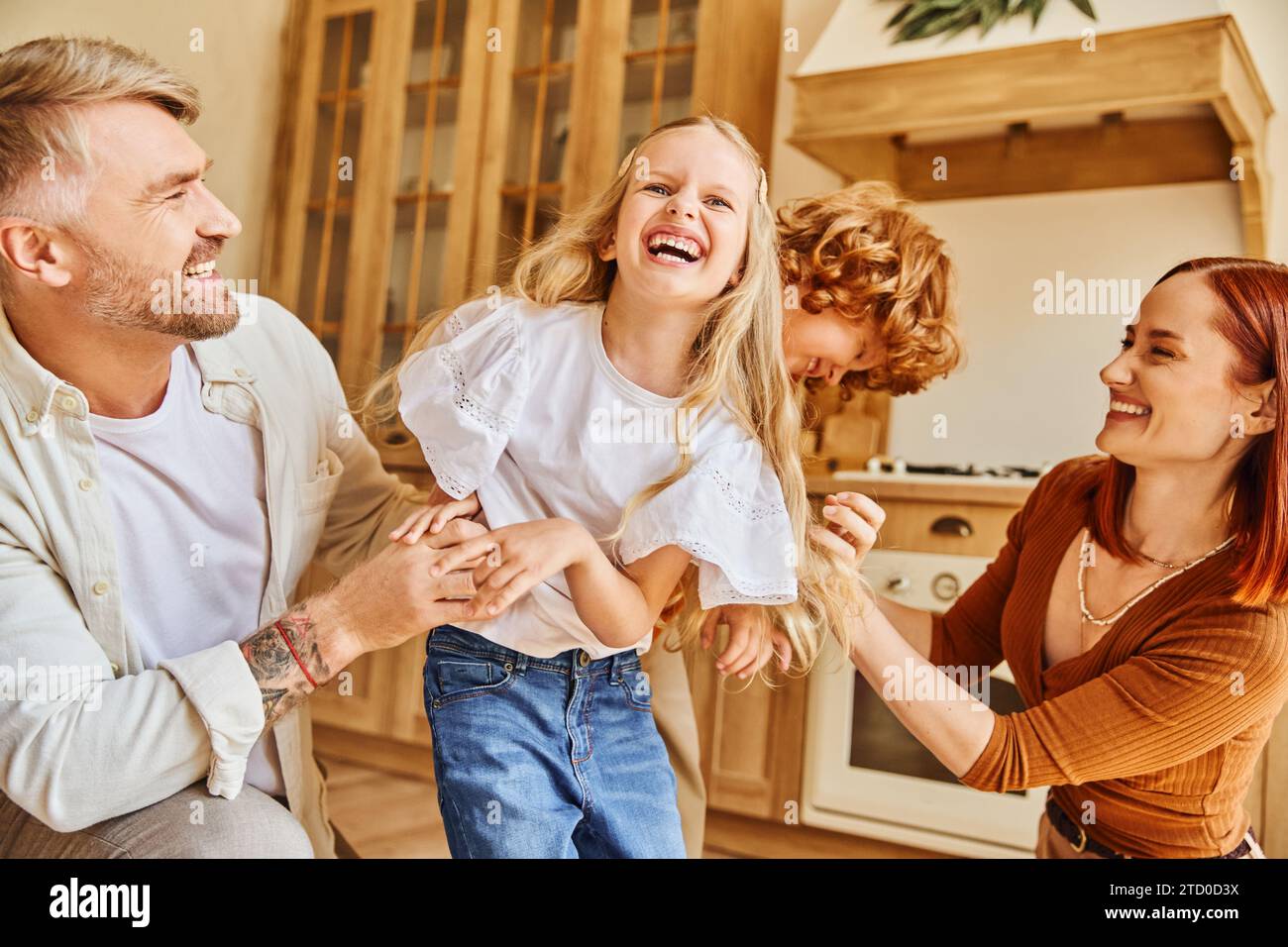 loving parents tickling excited kids in modern kitchen, fun and ...