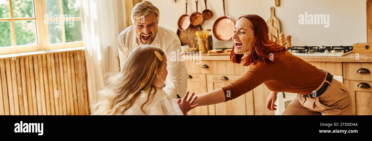 excited parents playing with happy daughter in modern kitchen at home ...