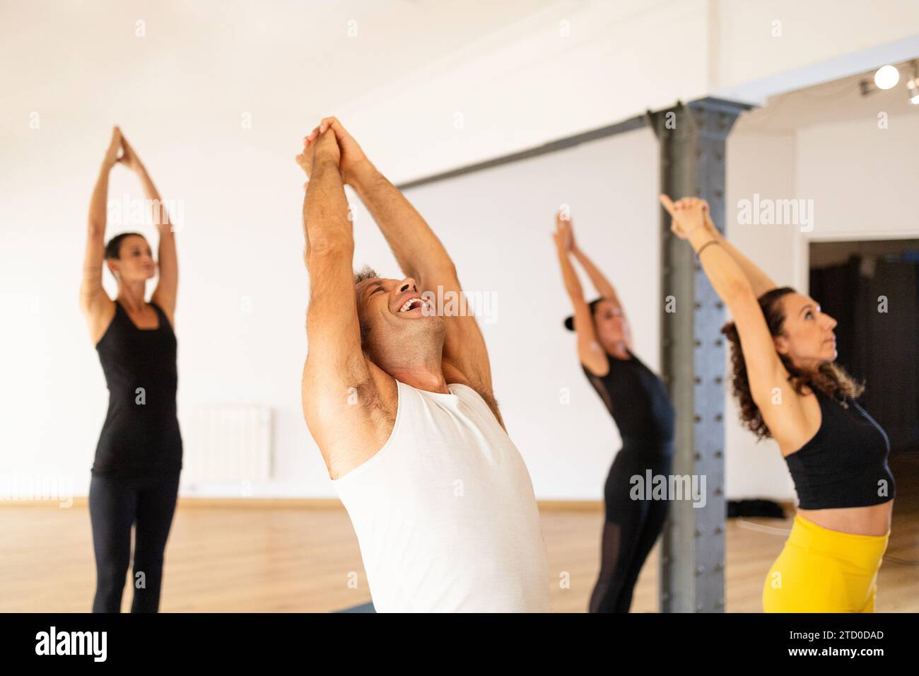 A diverse group of individuals engaged in a yoga session, stretching ...