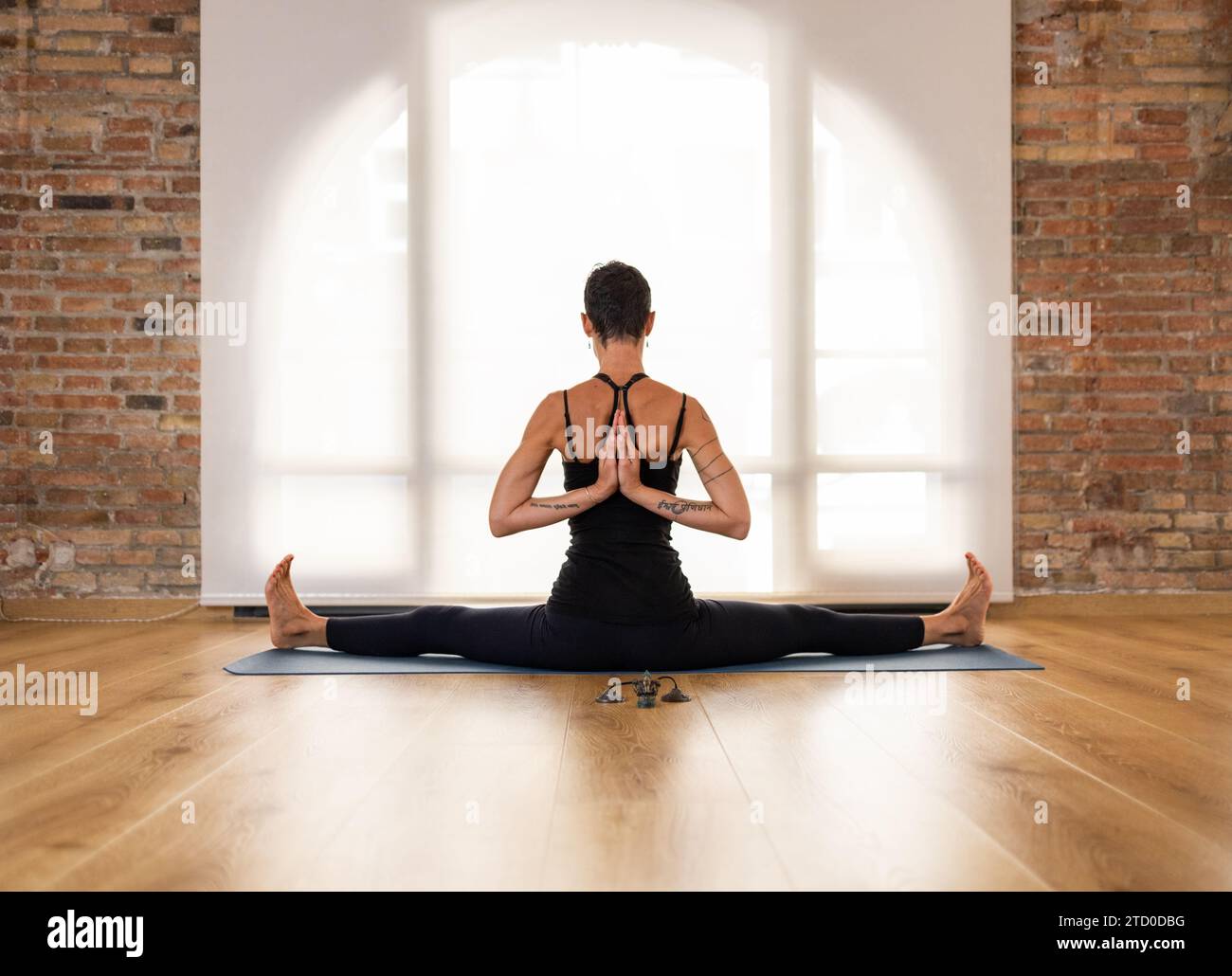A woman is captured from behind as she performs a splits pose while ...