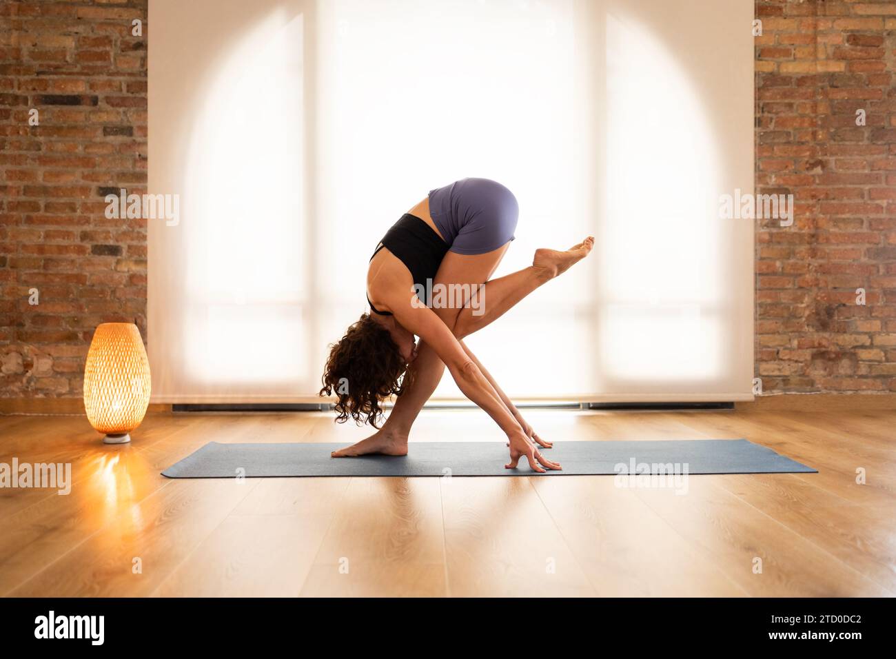 A woman in fitness attire is seen performing a yoga pose on a mat in a ...