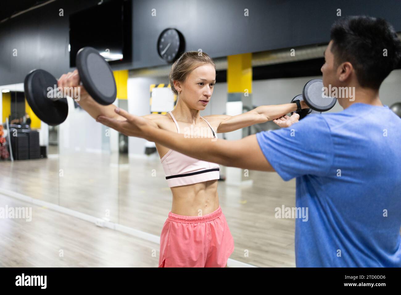 A focused female trainee is performing chest fly exercises with ...