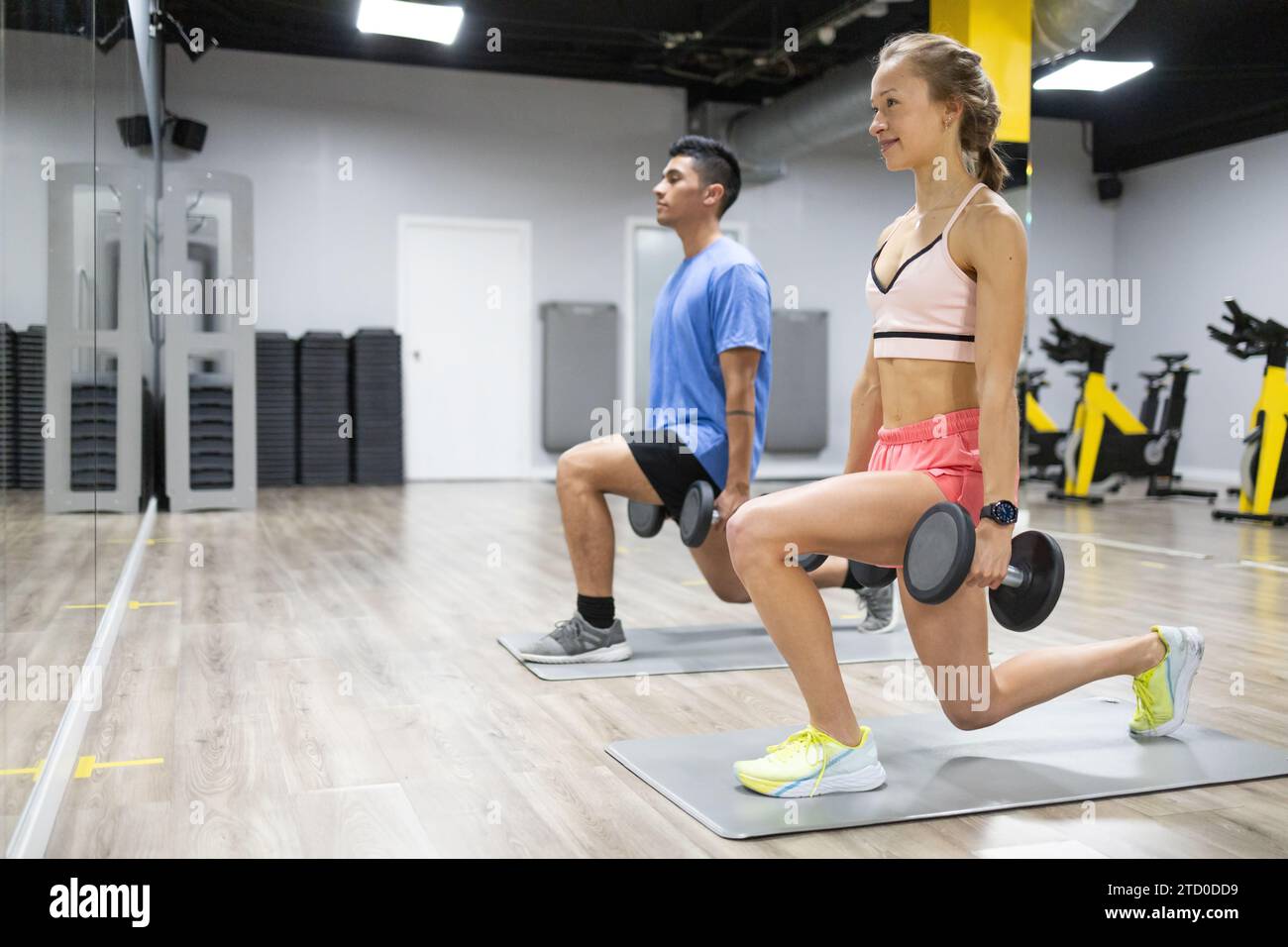 Two people are engaged in a workout session, performing lunges with ...