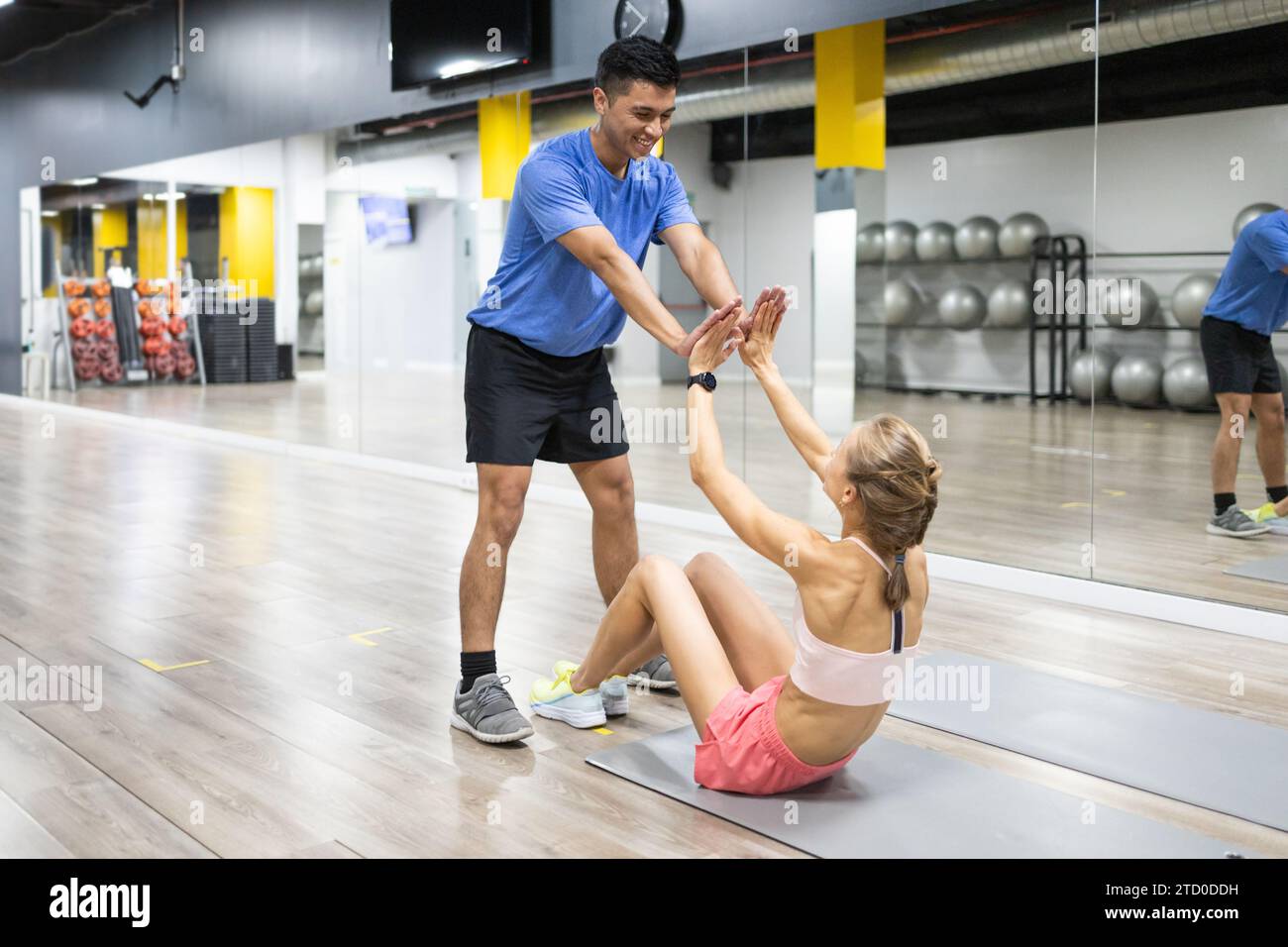 A personal trainer congratulates a female client with a high five as ...