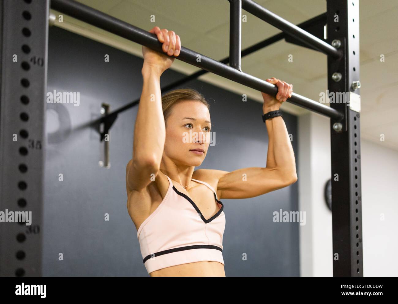 A focused female athlete engages in a pull-up workout, demonstrating ...