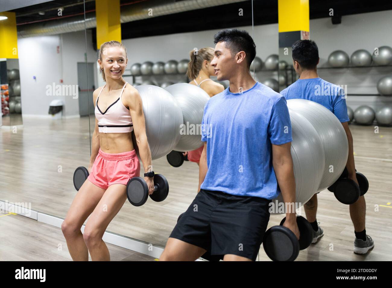 A mixed gender group smiling during a fitness class, holding exercise ...