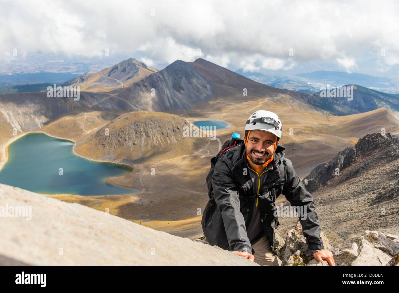 A smiling hiker wearing a helmet climbs Nevado de Toluca's rocky ...