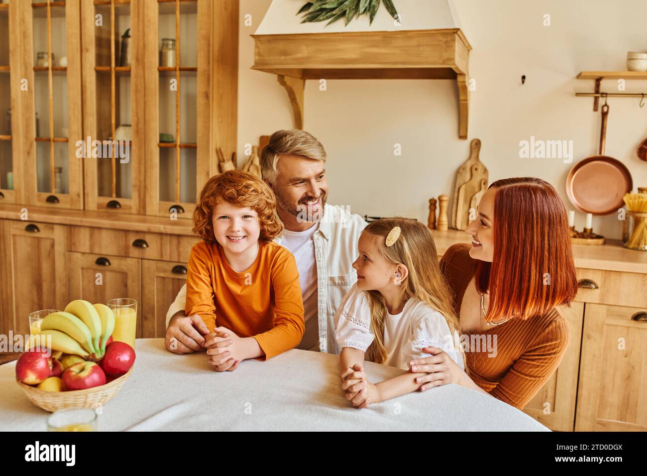 smiling parents with daughter and son sitting near fresh fruits and ...