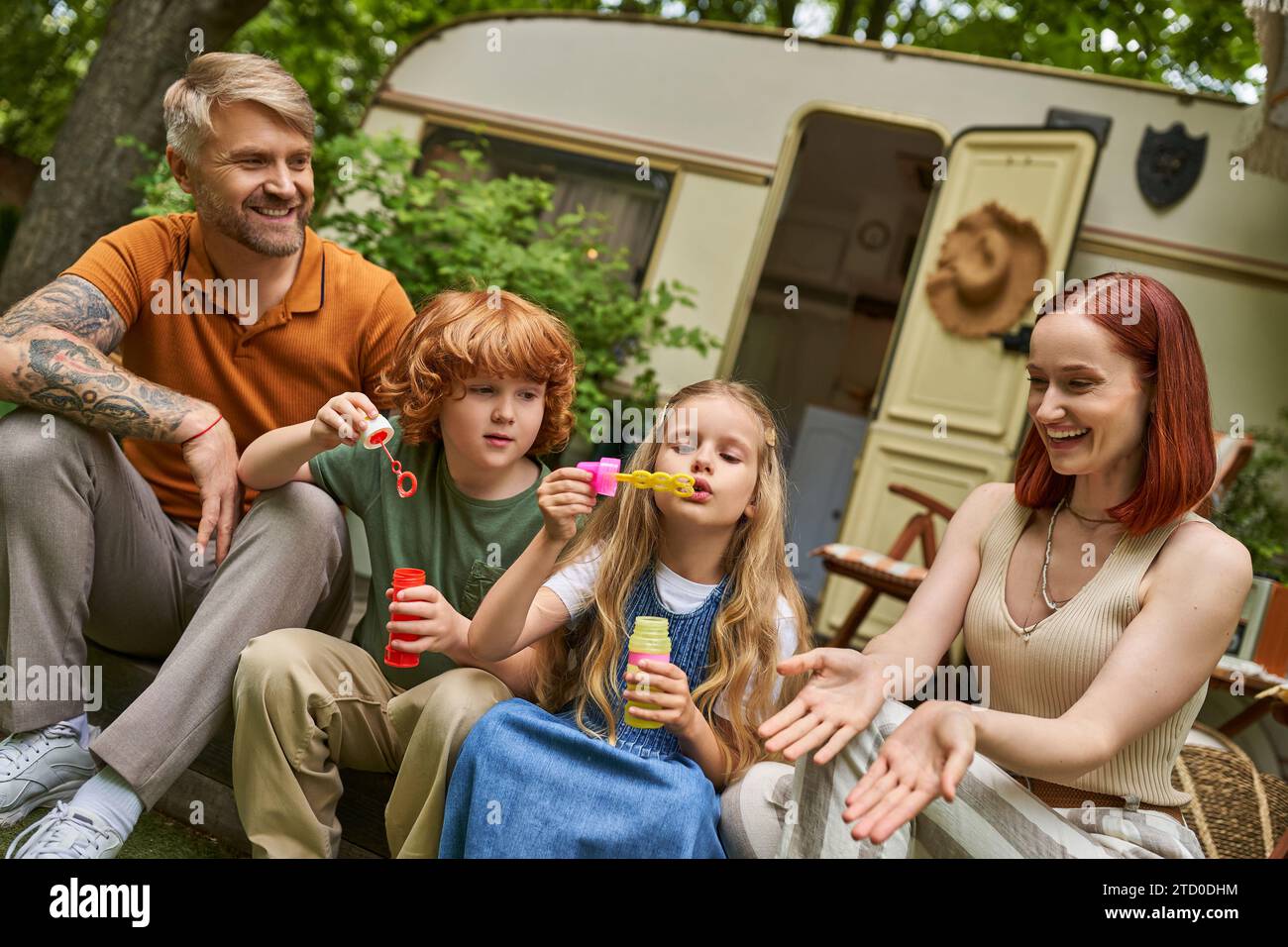 cute children blowing soap bubbles near happy parents next to modern ...