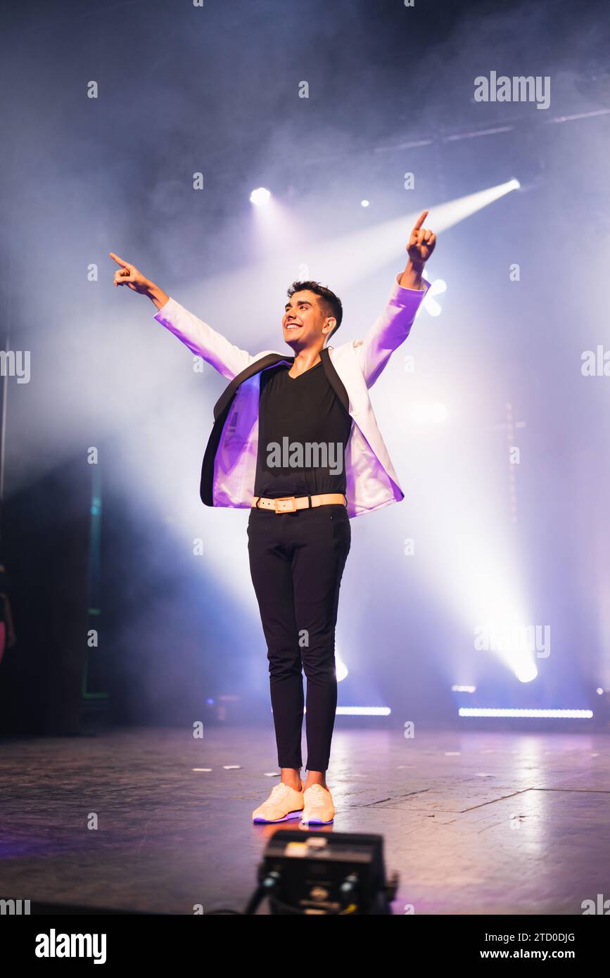 Full body of smiling illusionist standing on stage with smoke and ...