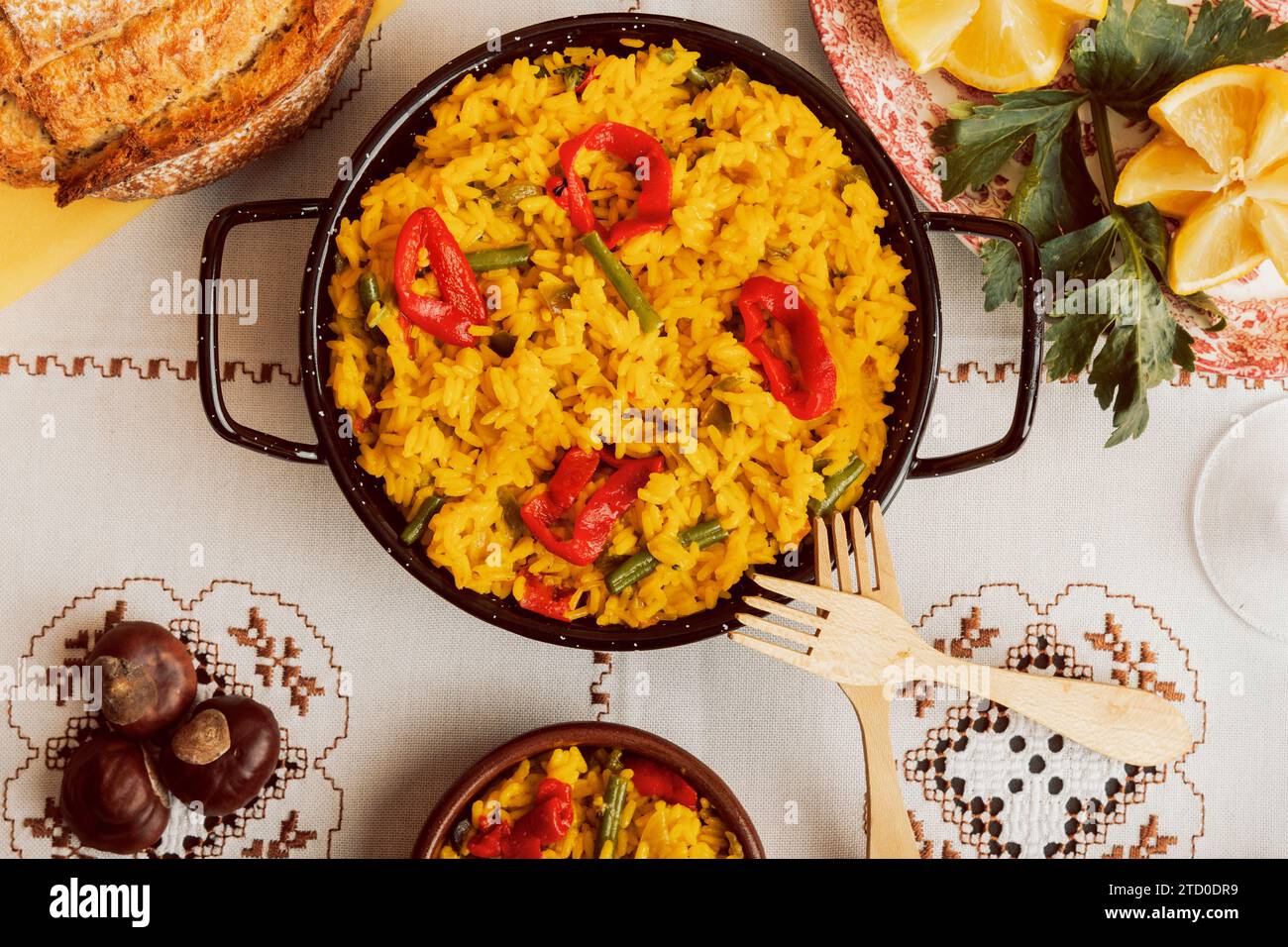 Paella served in traditional pan with lemon and tomato garnish ...