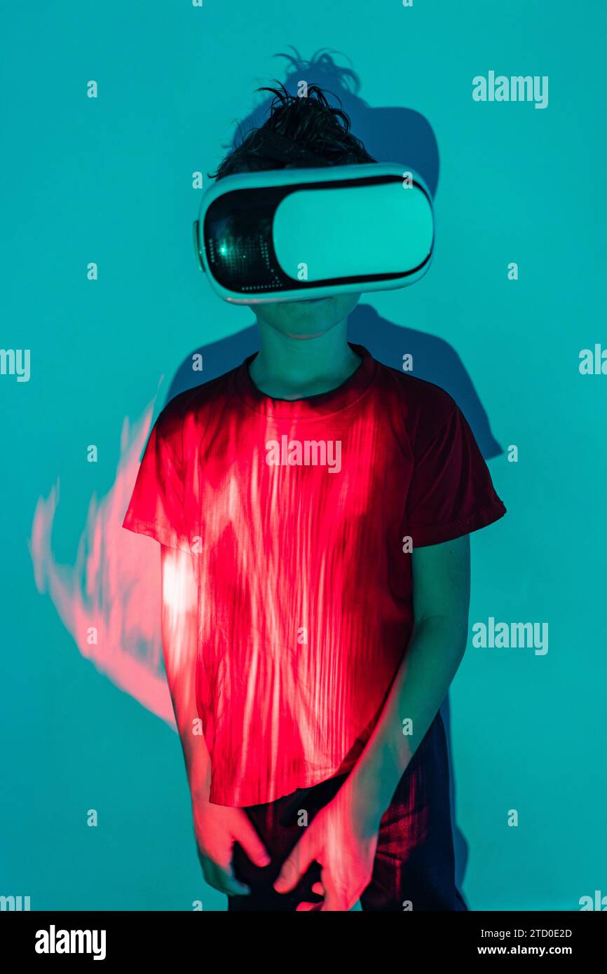 Boy in casual clothes and modern VR goggles experiencing virtual ...
