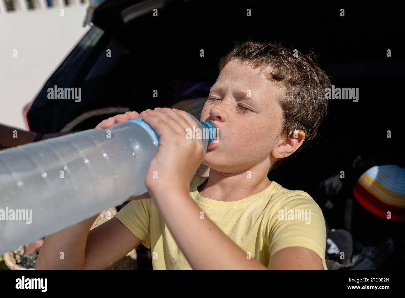 Little boy drinking water from plastic bottle while closed eyes in ...