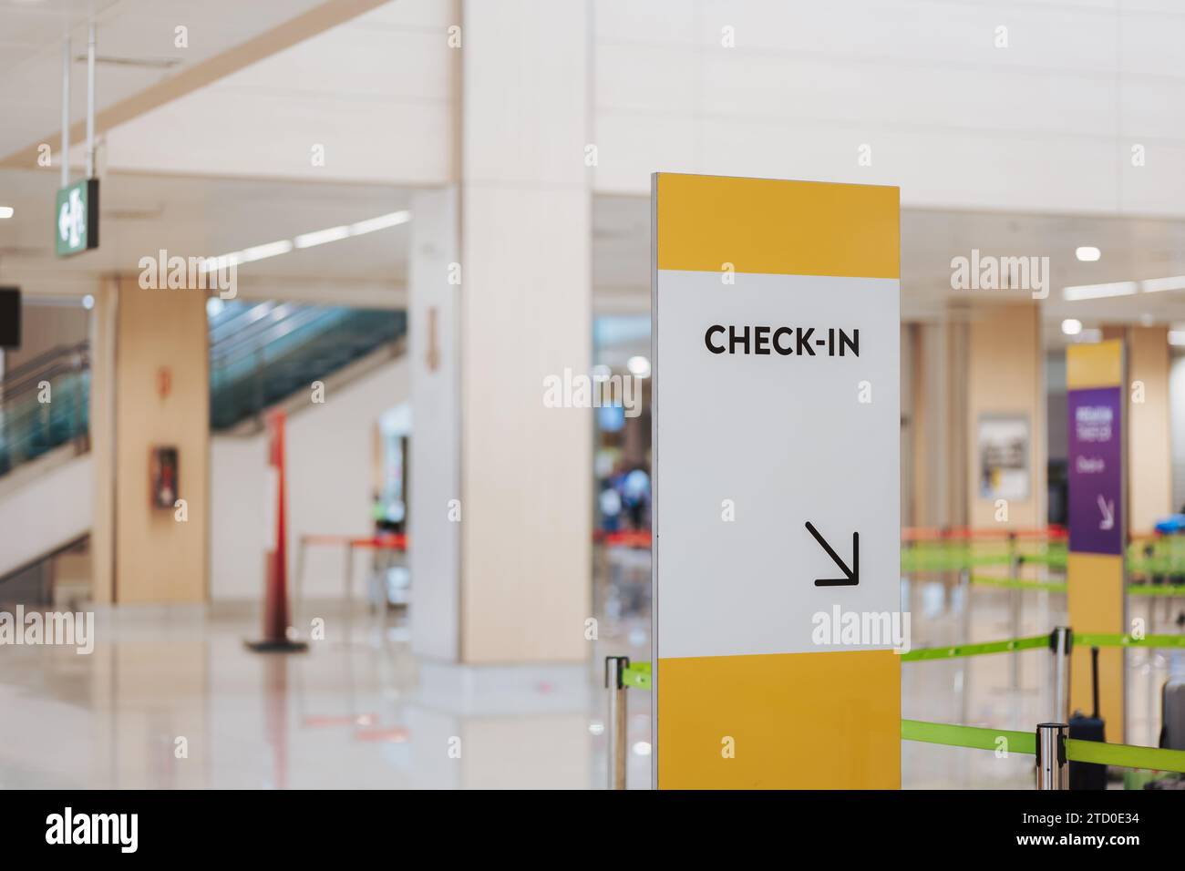 Yellow and white check-in directional sign at an airport with blurred ...