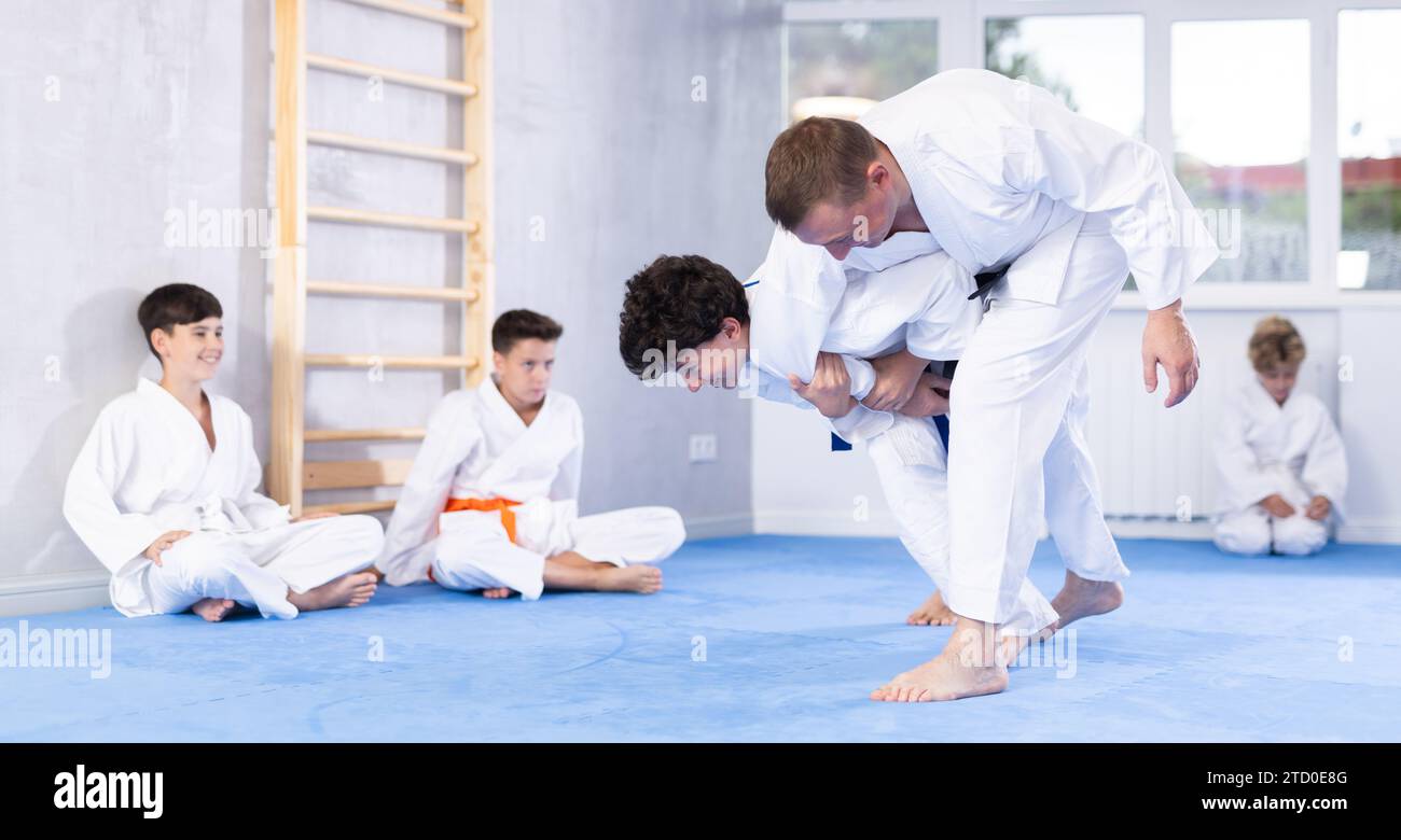 Skilled judo trainer demonstrating wrestling technique on juvenile ...