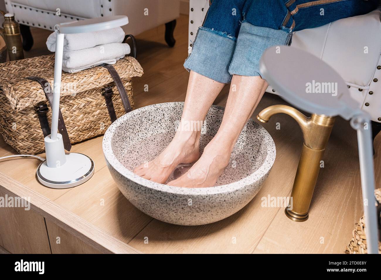 Crop anonymous female with feet dipped in water in bowl enjoying ...