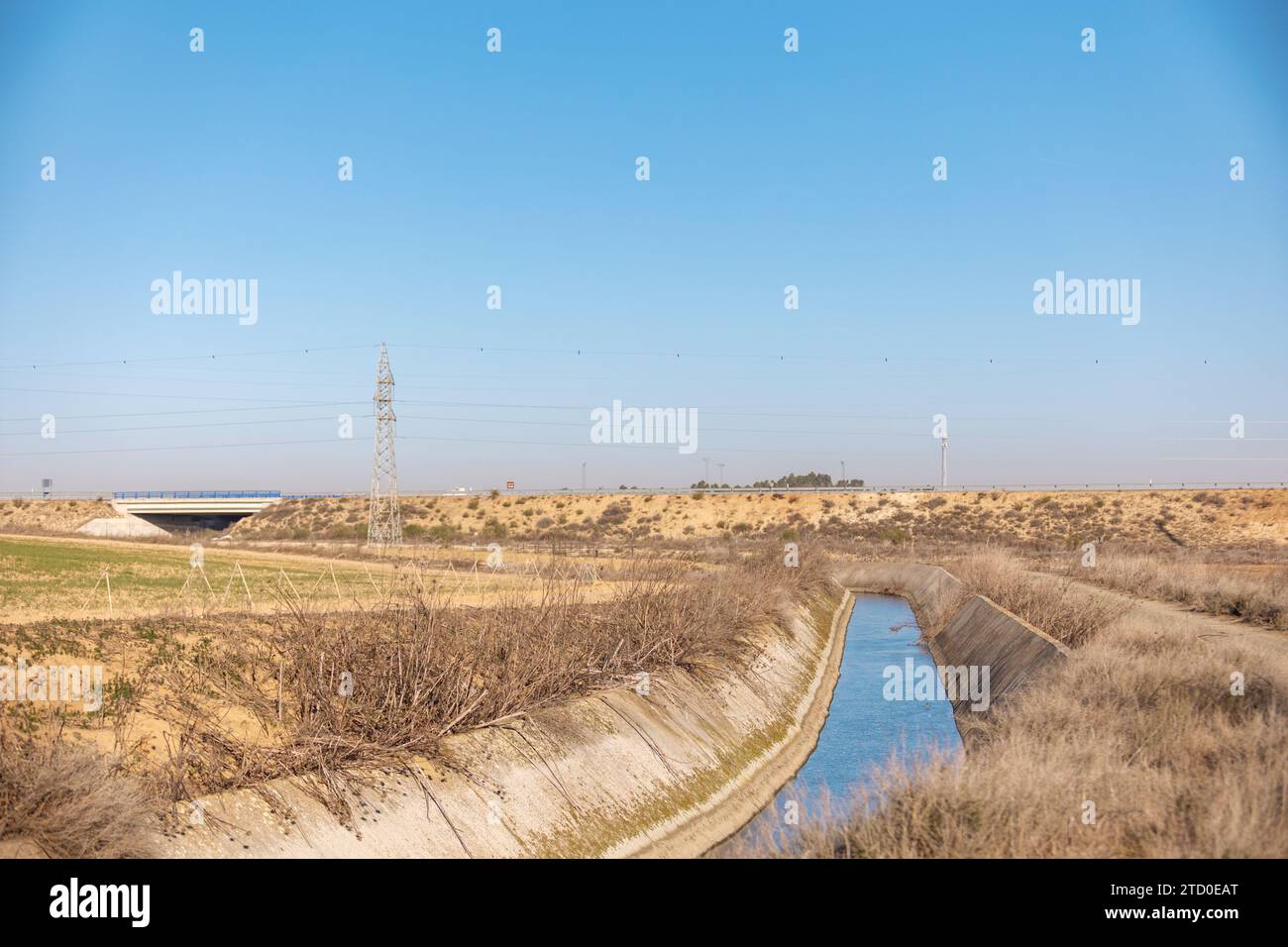 An irrigation canal winds through a dry, barren landscape with an ...