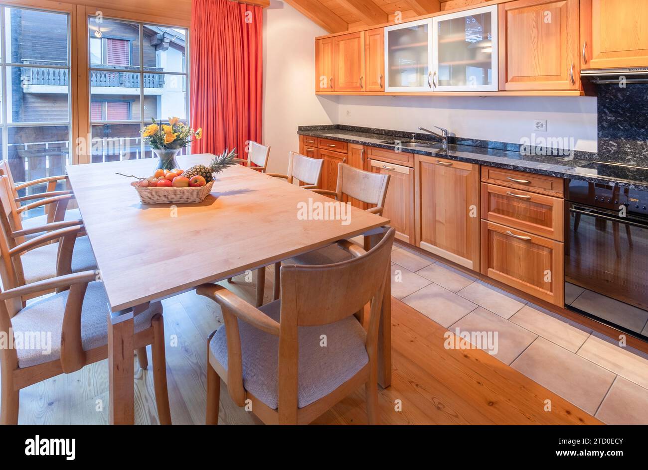 Inviting Swiss-style kitchen with wooden dining table set, fruit basket ...