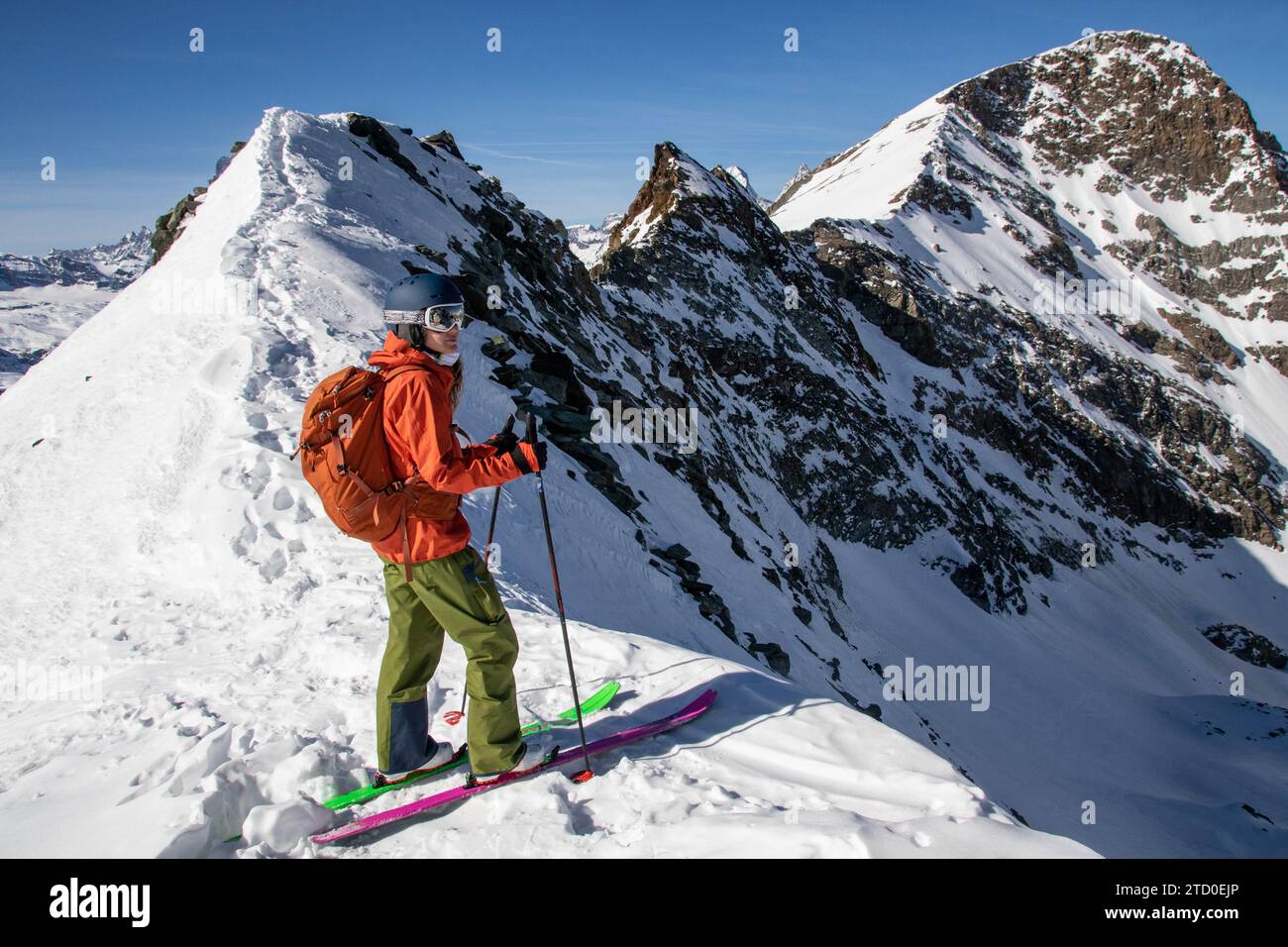 Side view of female backpacker standing on snowy mountain with ski ...
