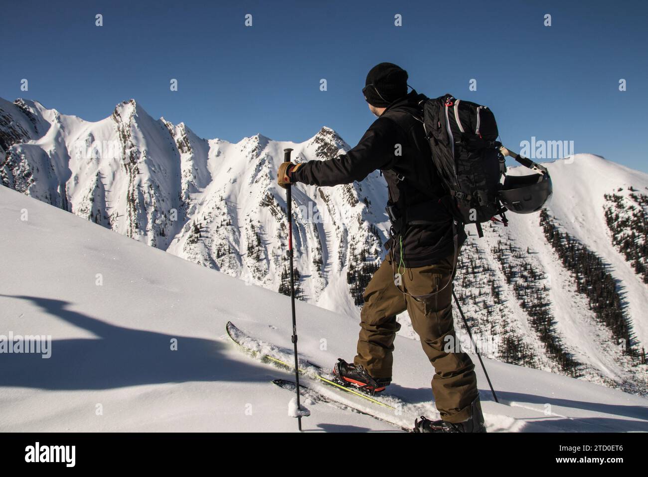 Side view of anonymous active skier with poles and backpack skiing on ...