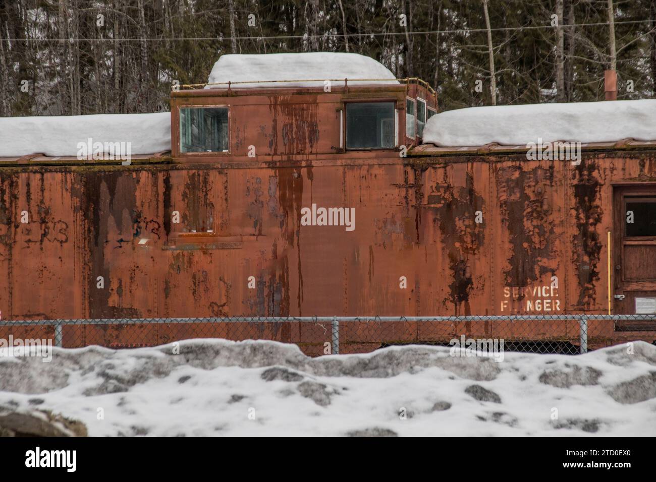 Old rusty brown locomotive and rocks covered in snow during winter ...