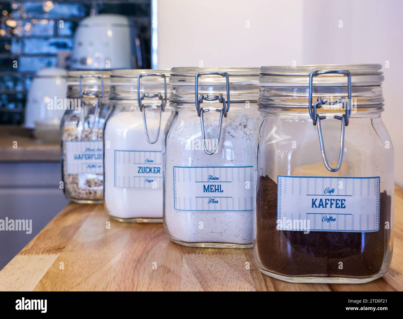 Four glass jars with metal clasps on a wooden counter, labeled with ...