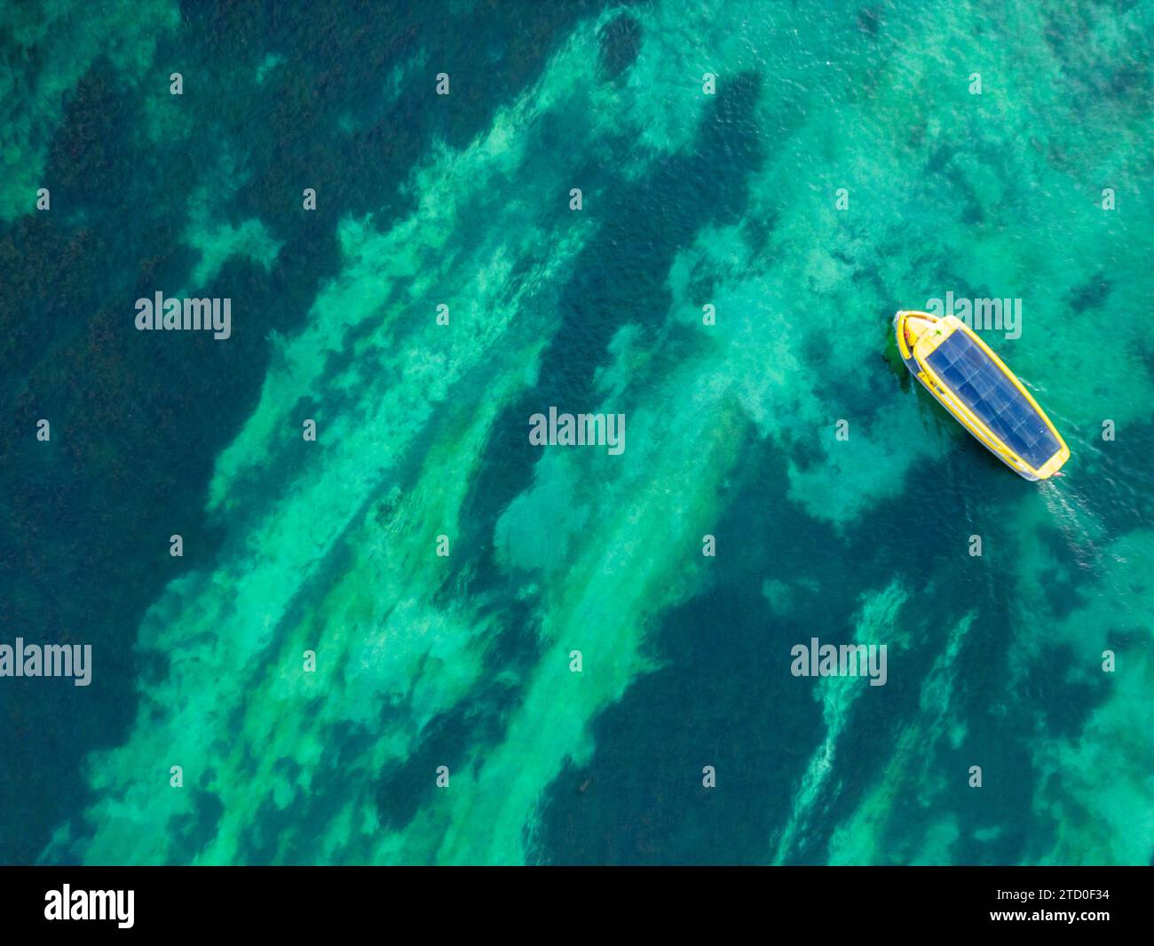 An aerial shot captures a lone boat floating on the translucent blue ...