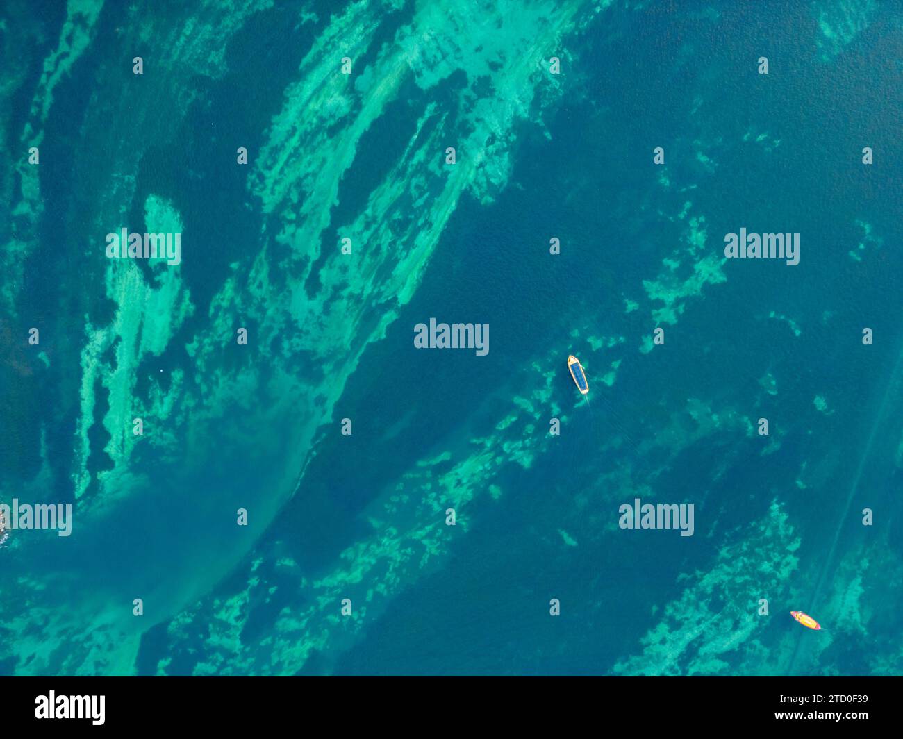 This image captures a boat from above as it navigates lake waters that ...