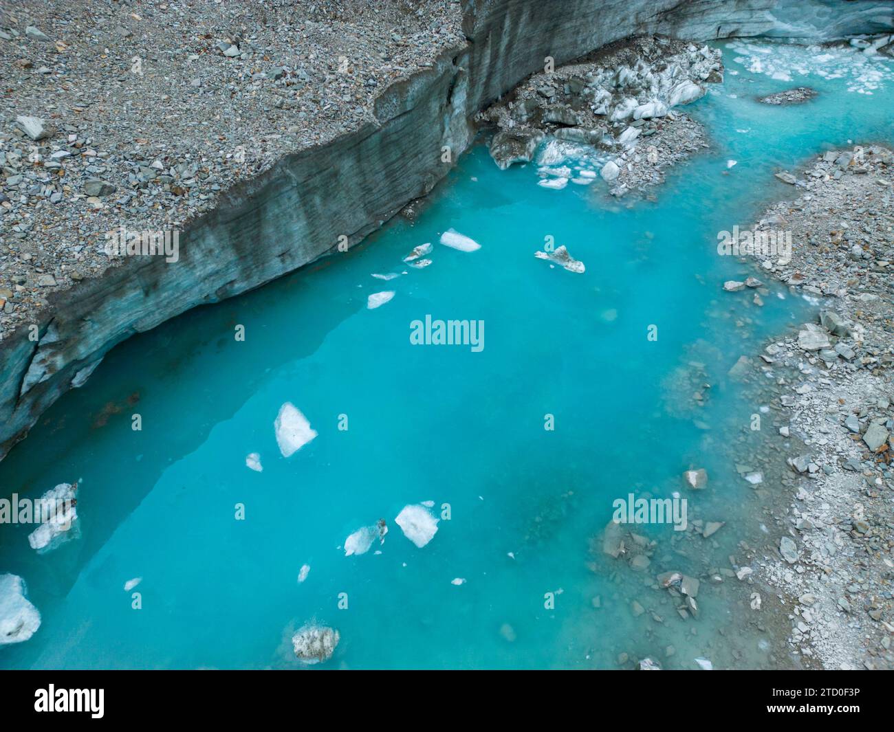 A vibrant turquoise glacial river flows through a rocky landscape with ...