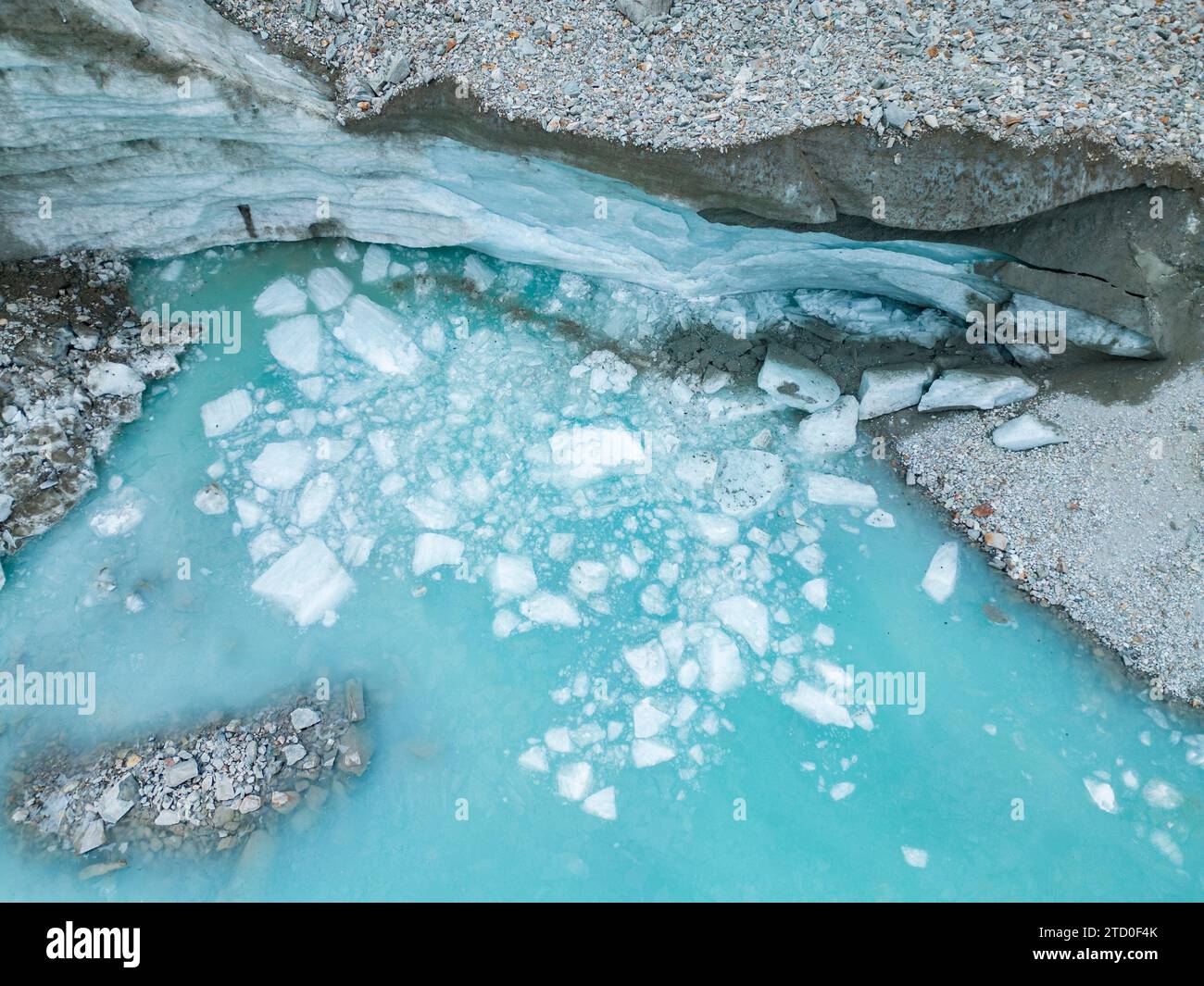 A serene view of a partially frozen lake with clear blue water and ...