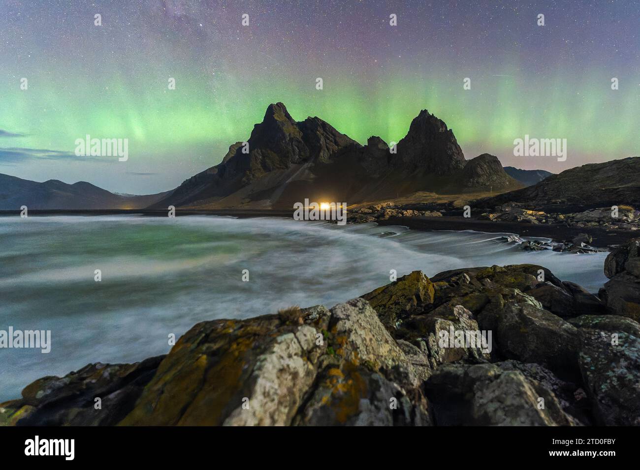 The mesmerizing Northern Lights cascade over a rugged coastline with ...