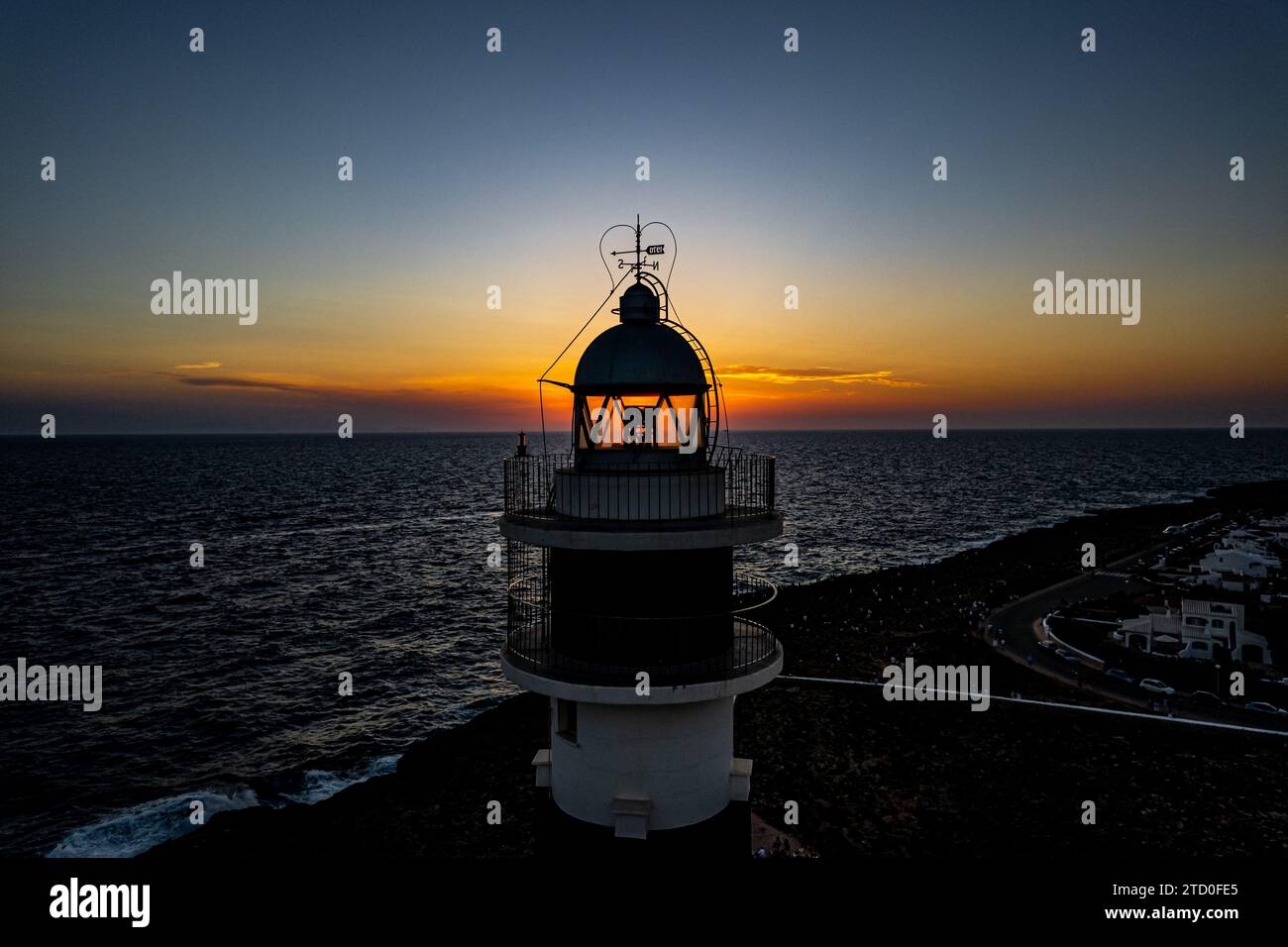 The Faro d'Artrutx lighthouse stands against a vibrant sunset sky in ...