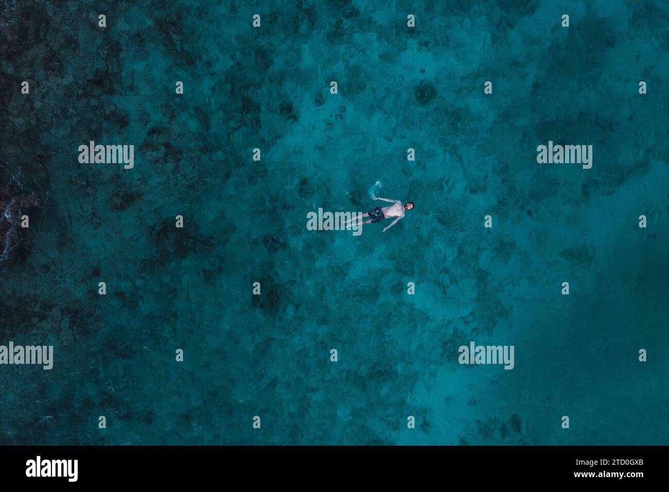 An aerial perspective captures a lone swimmer above the stunning, clear ...