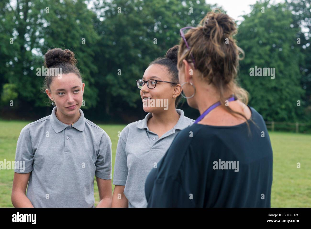 A group of girls in a British High School stand outside talking to a ...