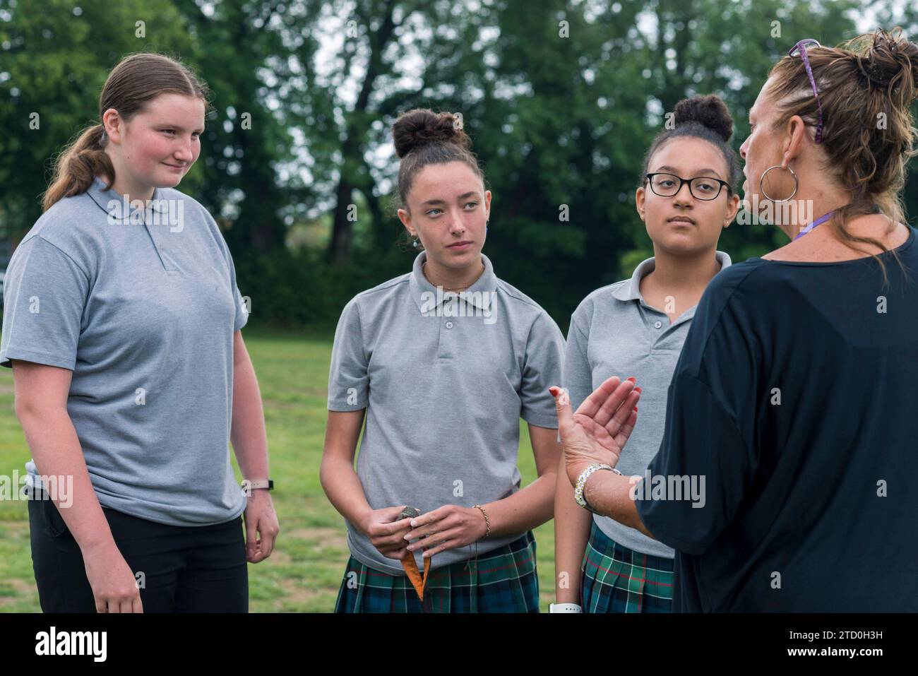 A group of girls in a British High School stand outside talking to a ...