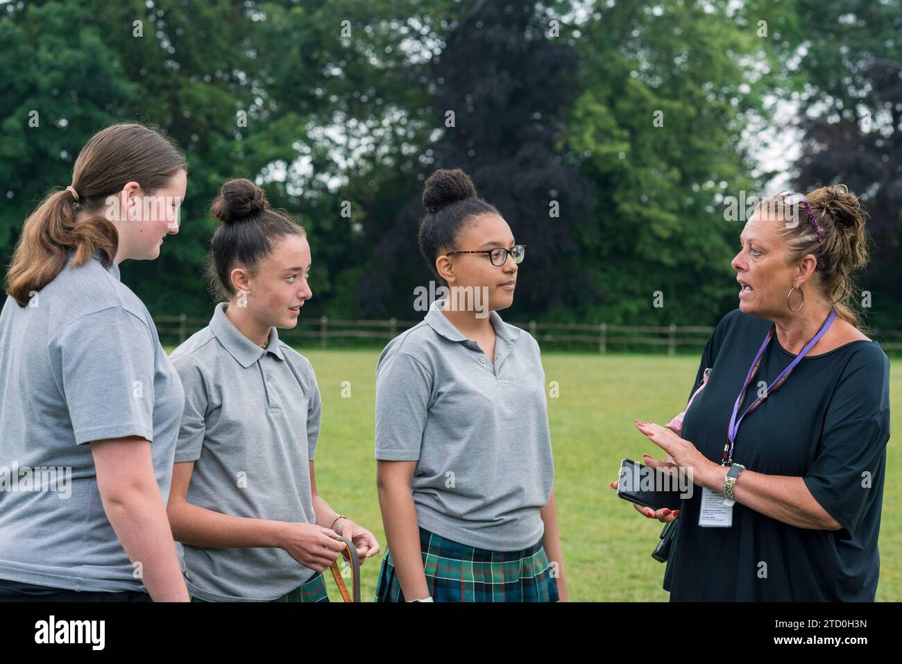 A group of girls in a British High School stand outside talking to a ...
