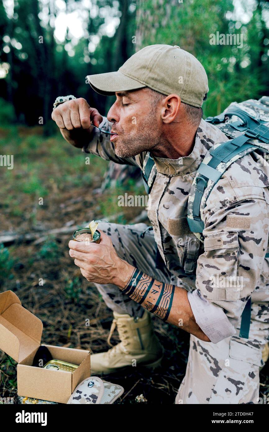 Side view of Mature military marine soldier eating from canned food ...