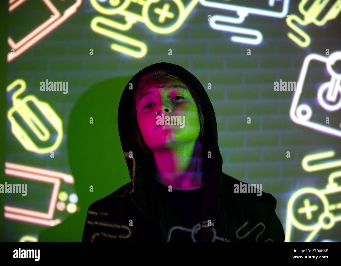 A young boy stands against a vibrant neon-lit background with a ...