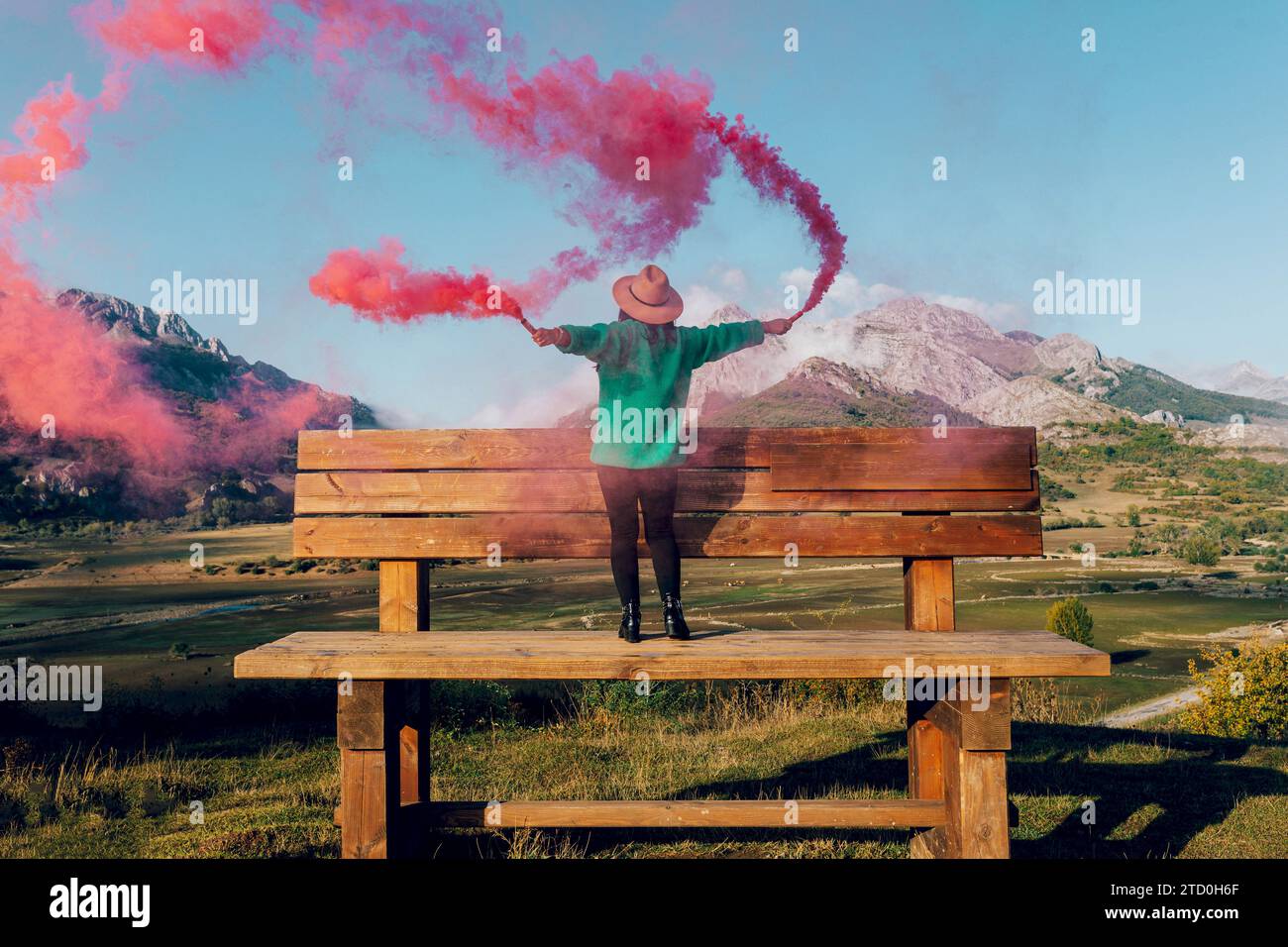 Back view of a woman standing on a big bench, arms outstretched ...