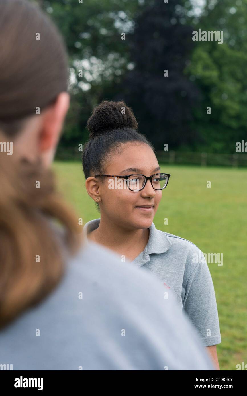 A group of girls in a British High School stand outside talking to a ...