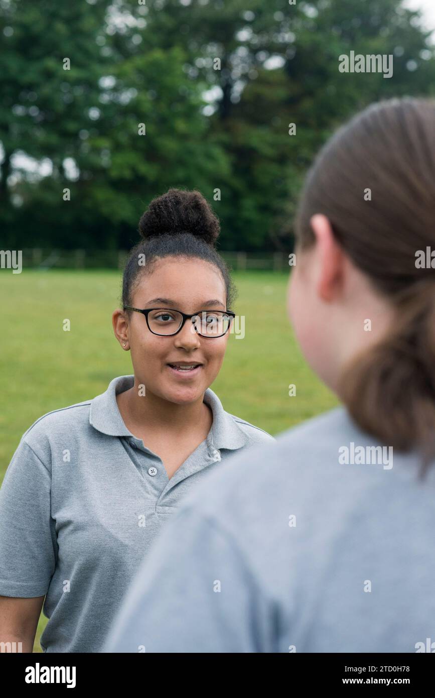 A group of girls in a British High School stand outside talking to a ...